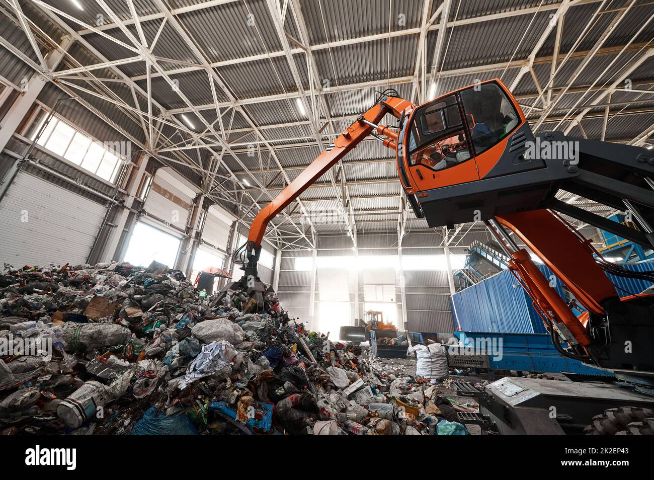 Excavator grabs trash in warehouse of waste processing plant Stock ...