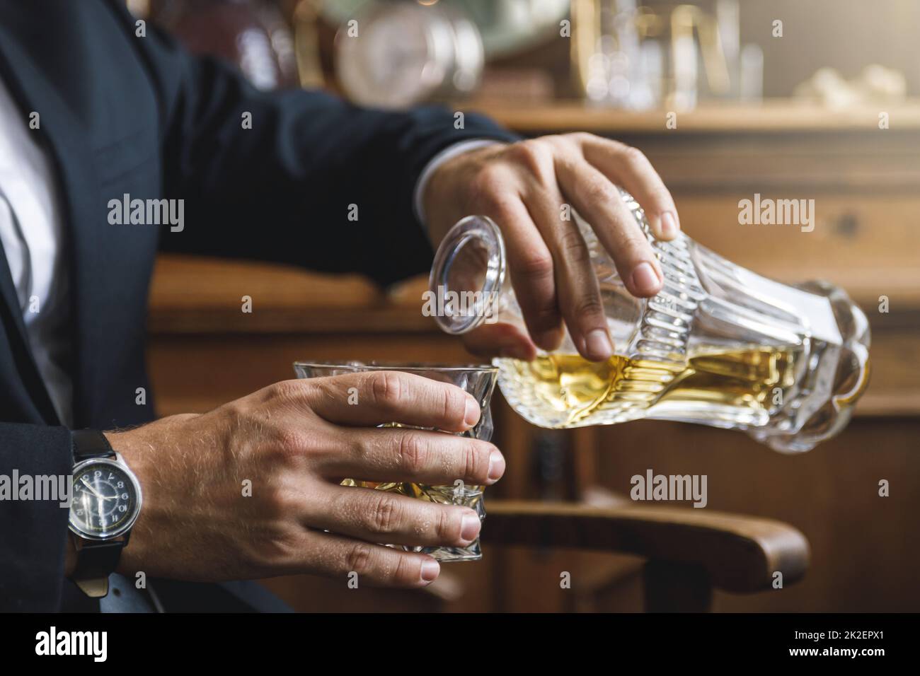 Man pouring whiskey into the crystal drinking glass Stock Photo - Alamy