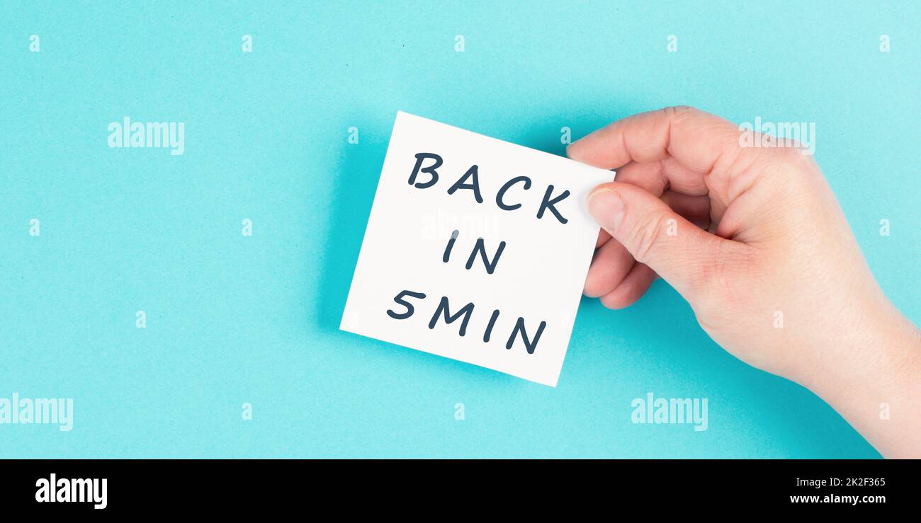 Back in 5 min ist standing on a paper, hands hold message, working ...