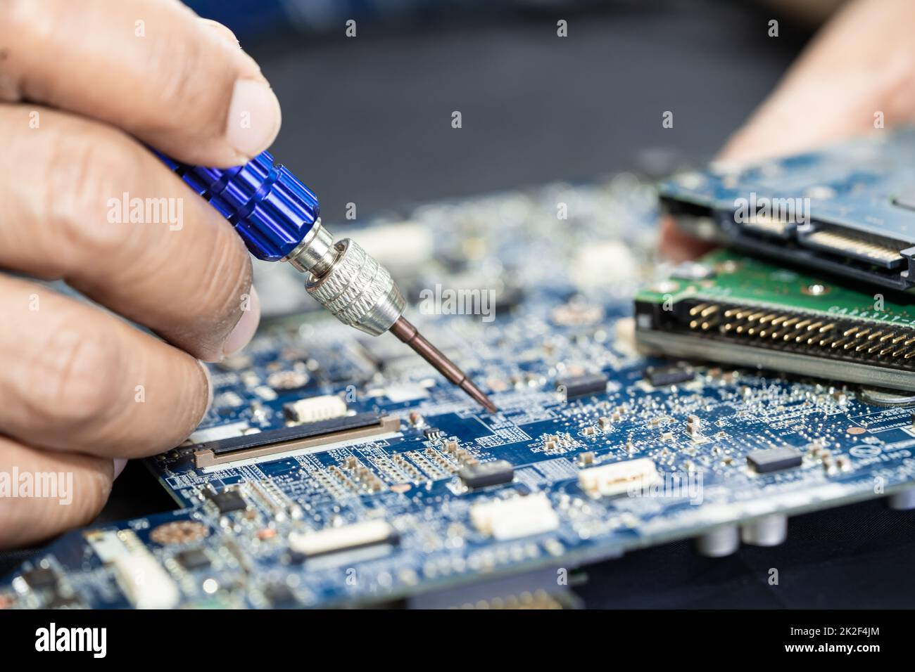 Technician repairing inside of printed circuit board PCB by soldering ...