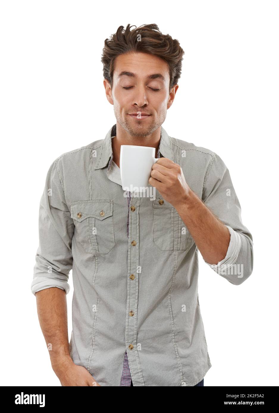 Fresh coffee smells amazing. A handsome young man enjoying the aroma of ...