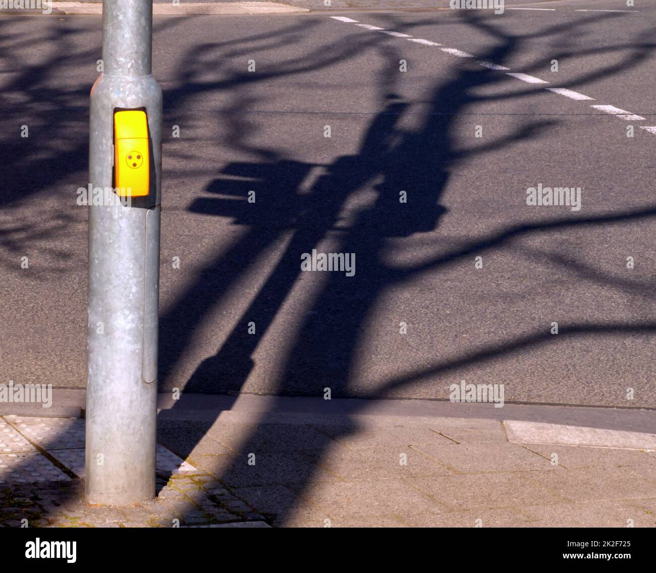 Shade of a traffic light on asphalt, yellow traffic light button for ...