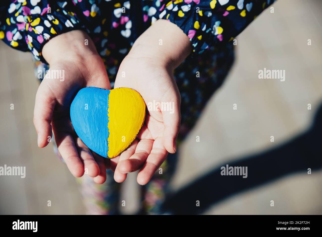 Small little kid hold heart shaped stone with Ukraine national flag or ...