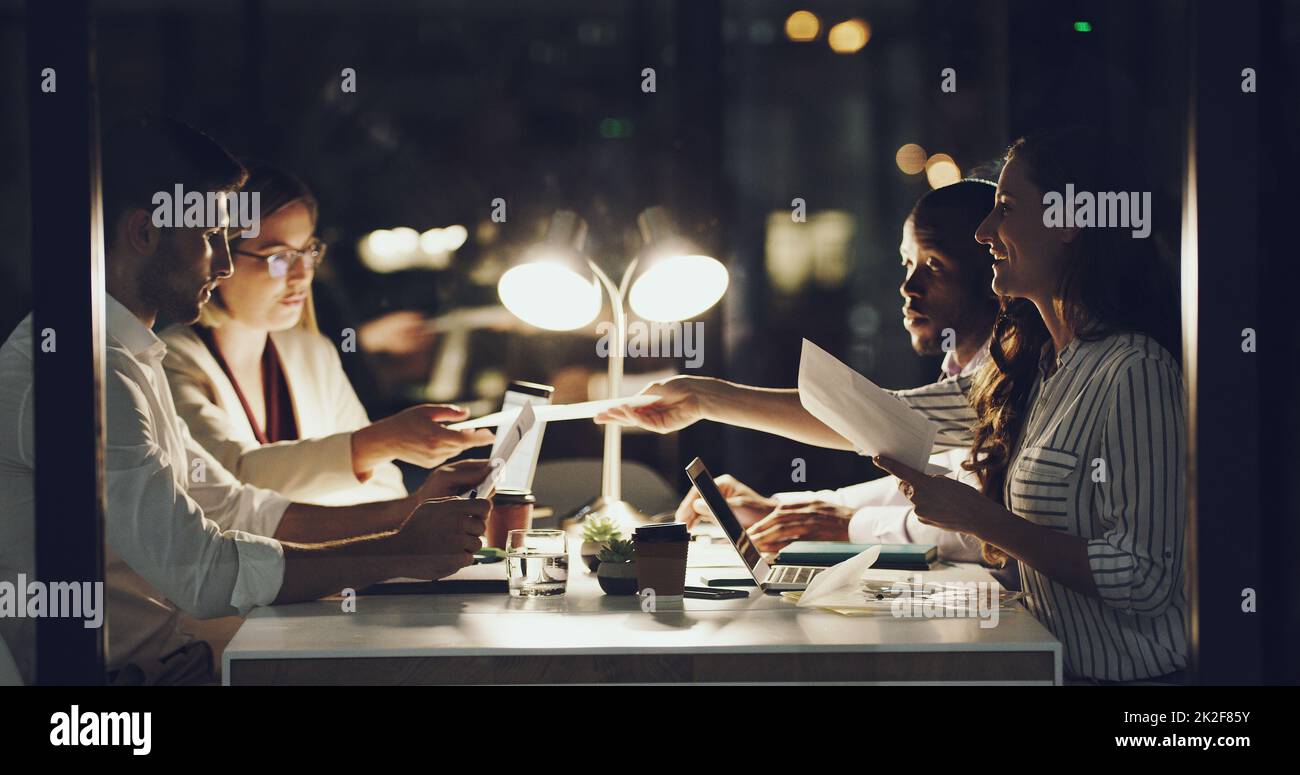 Working late into the night. Cropped shot of a group of businesspeople ...