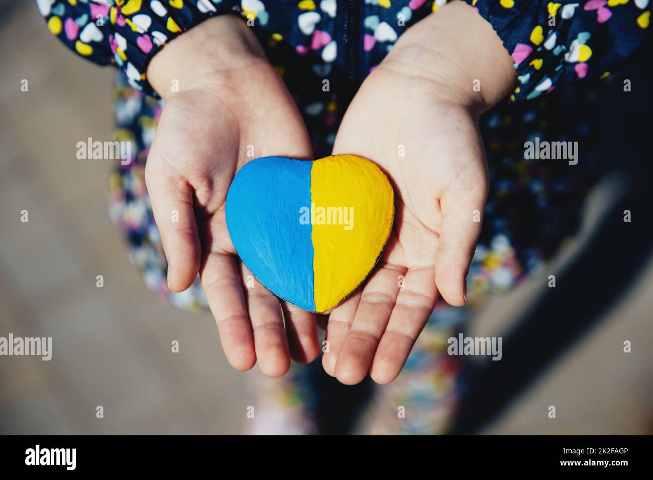 Small little kid hold heart shaped stone with Ukraine national flag or ...