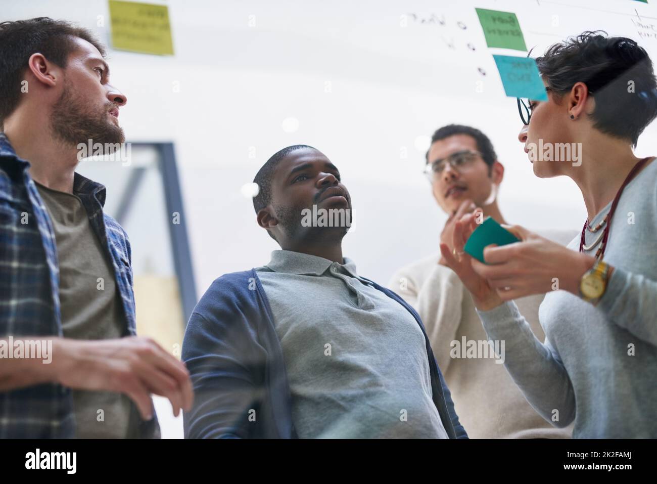 Planning with one sticky note at a time. Shot of a group of designers ...