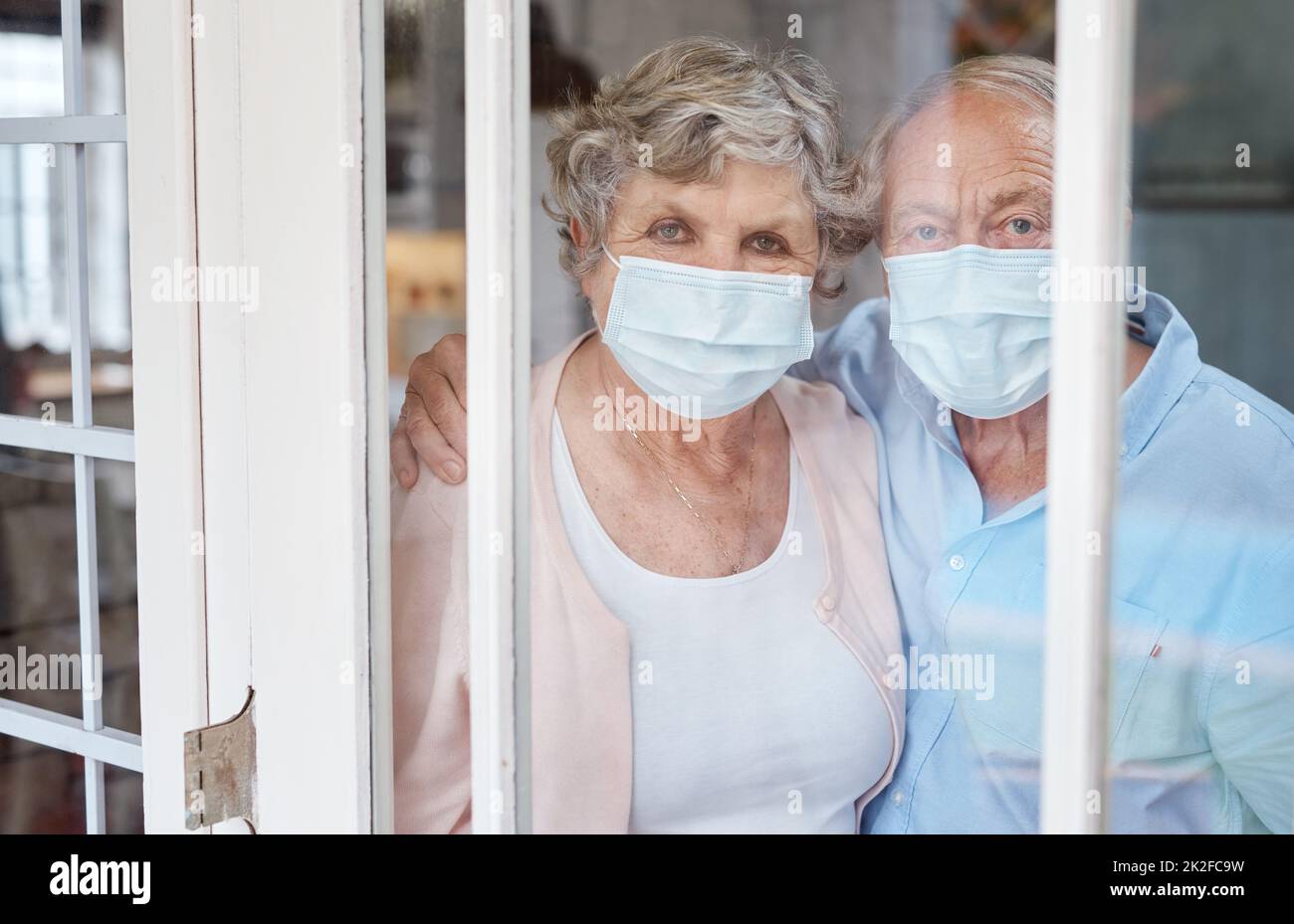 Love on an atom, love on a cloud. Portrait of a masked elderly couple at home in isolation ...