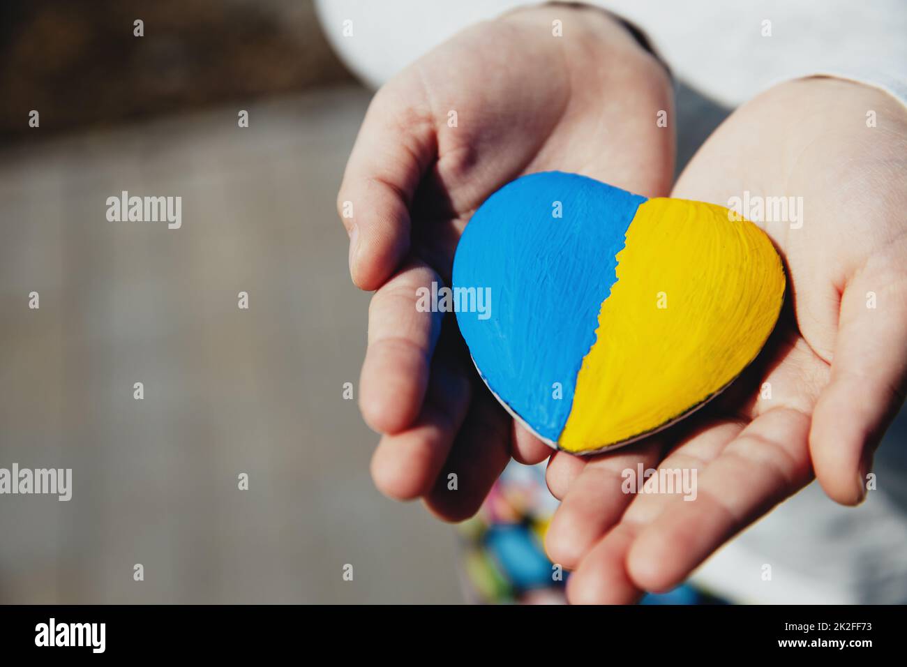 Small little kid hold heart shaped stone with Ukraine national flag or ...