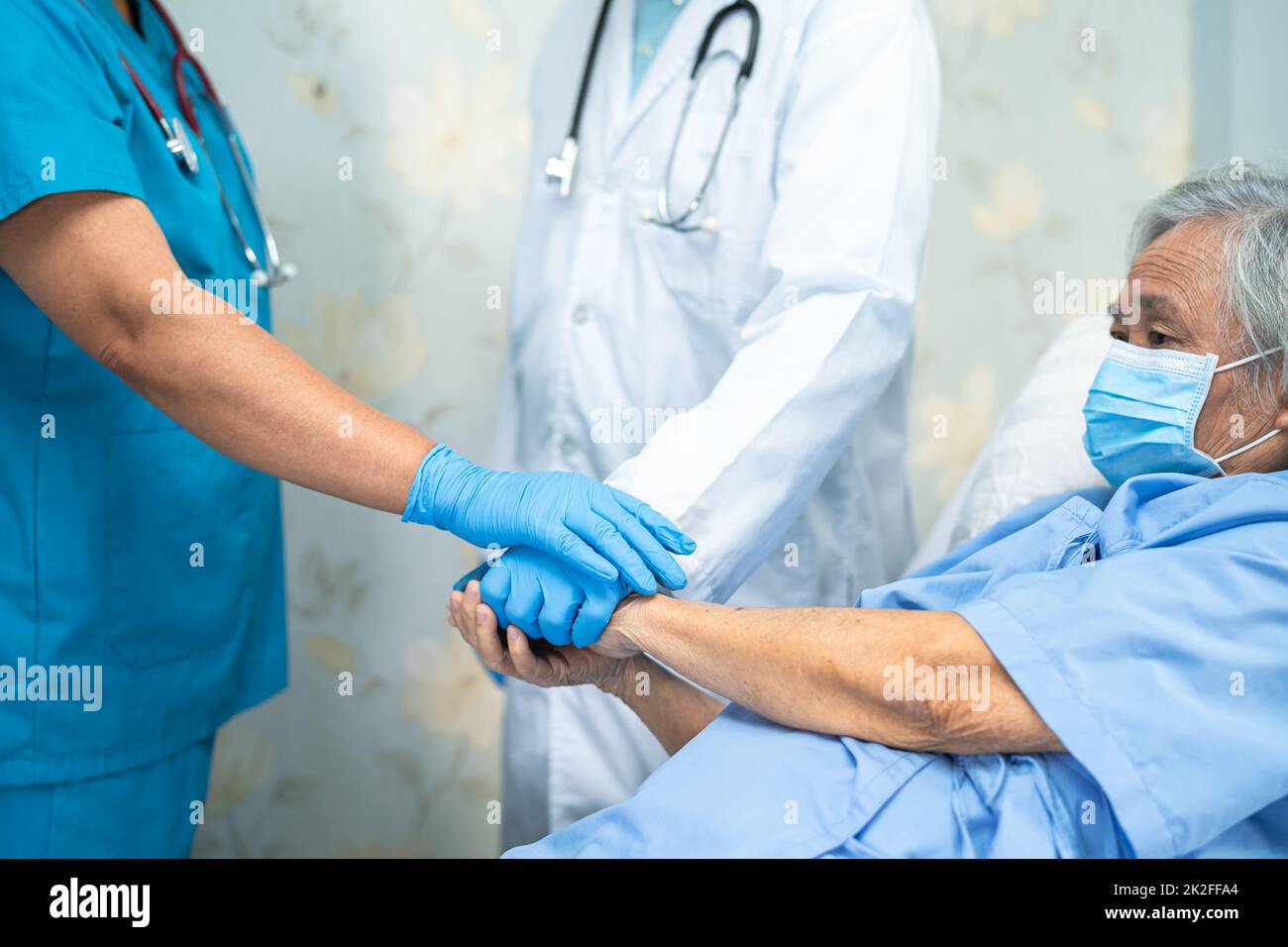 Asian doctor team and old senior lady patient stack hands together as ...