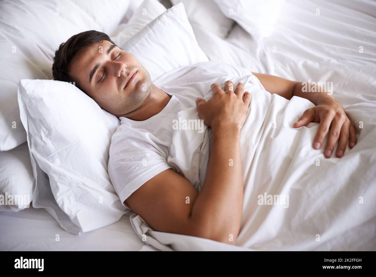 Well rested for a busy day. a young man sleeping in bed Stock Photo - Alamy