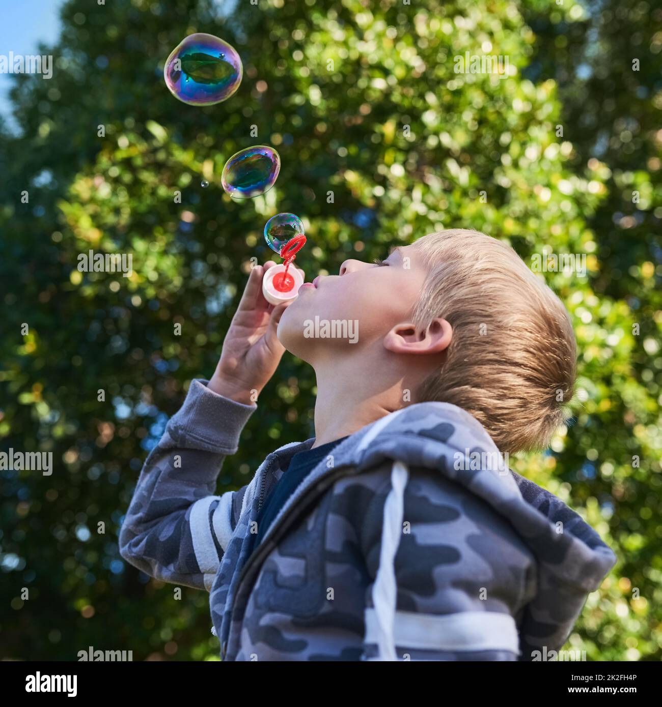 Who knows where the bubbles will go. Shot of a cute young boy blowing ...