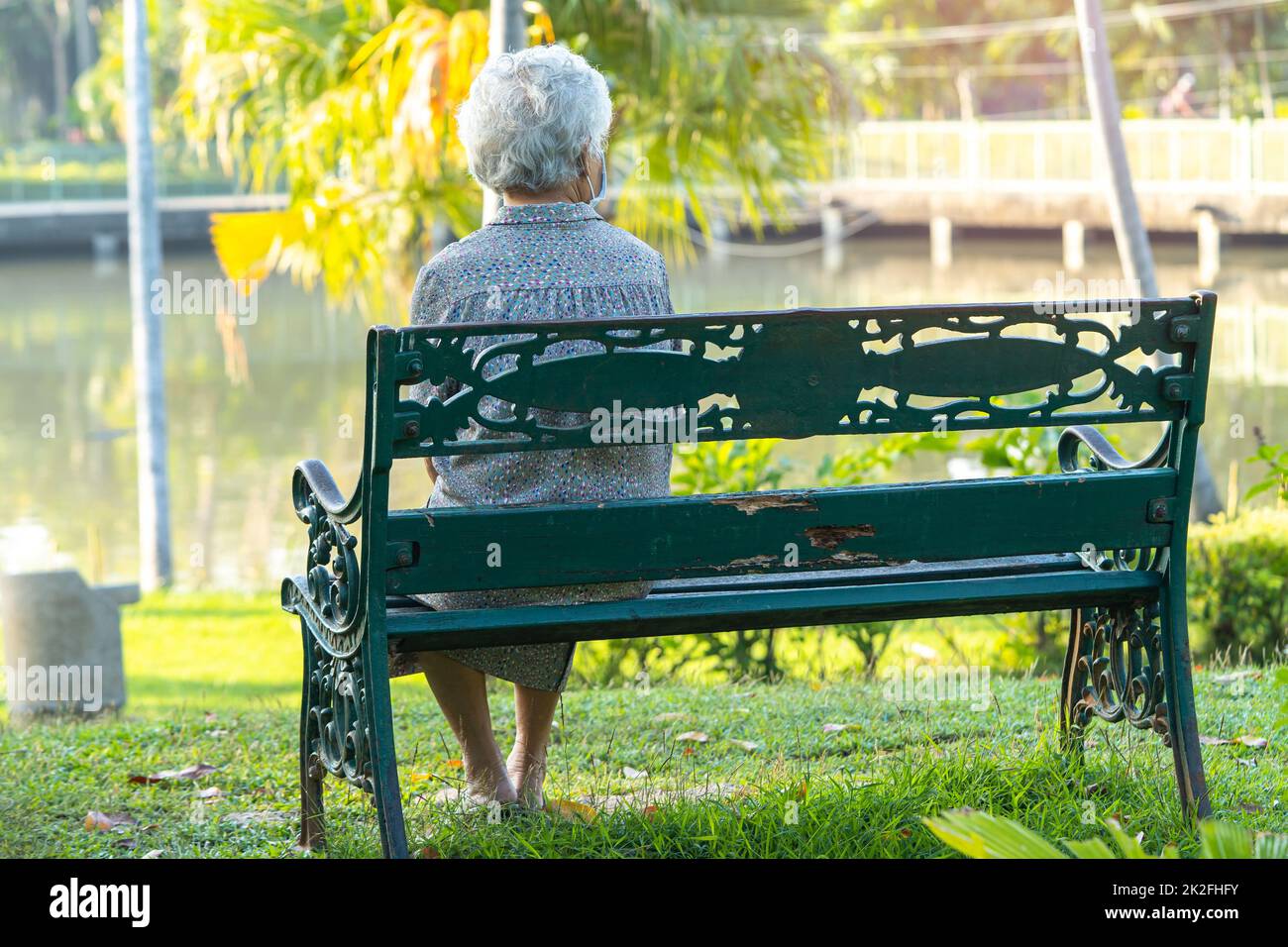 Asian elderly woman depressed and sad sitting back on bench in autumn ...