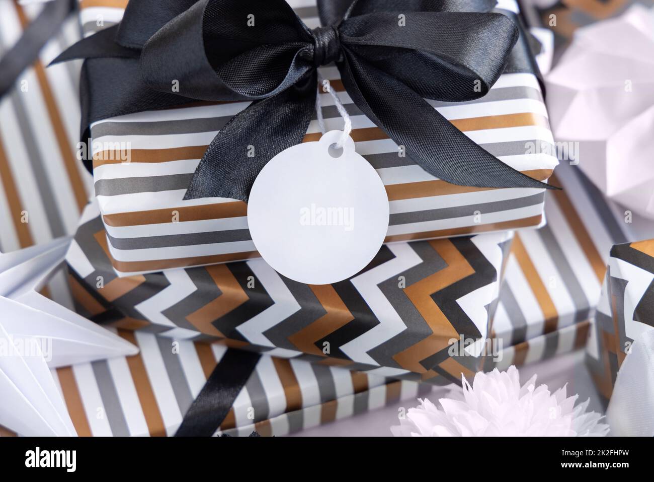 Wrapped present with round blank gift tag and black bow close up, label ...