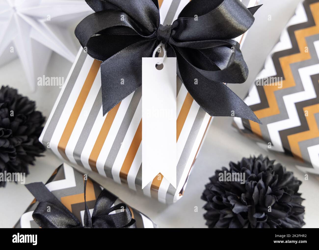 Wrapped present with blank gift tag and black bow close up, label ...