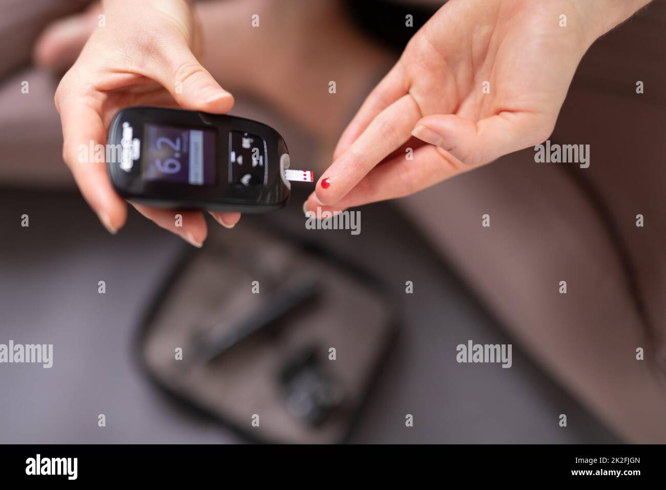 Blood sugar testing at home. Woman checking blood sugar level by ...