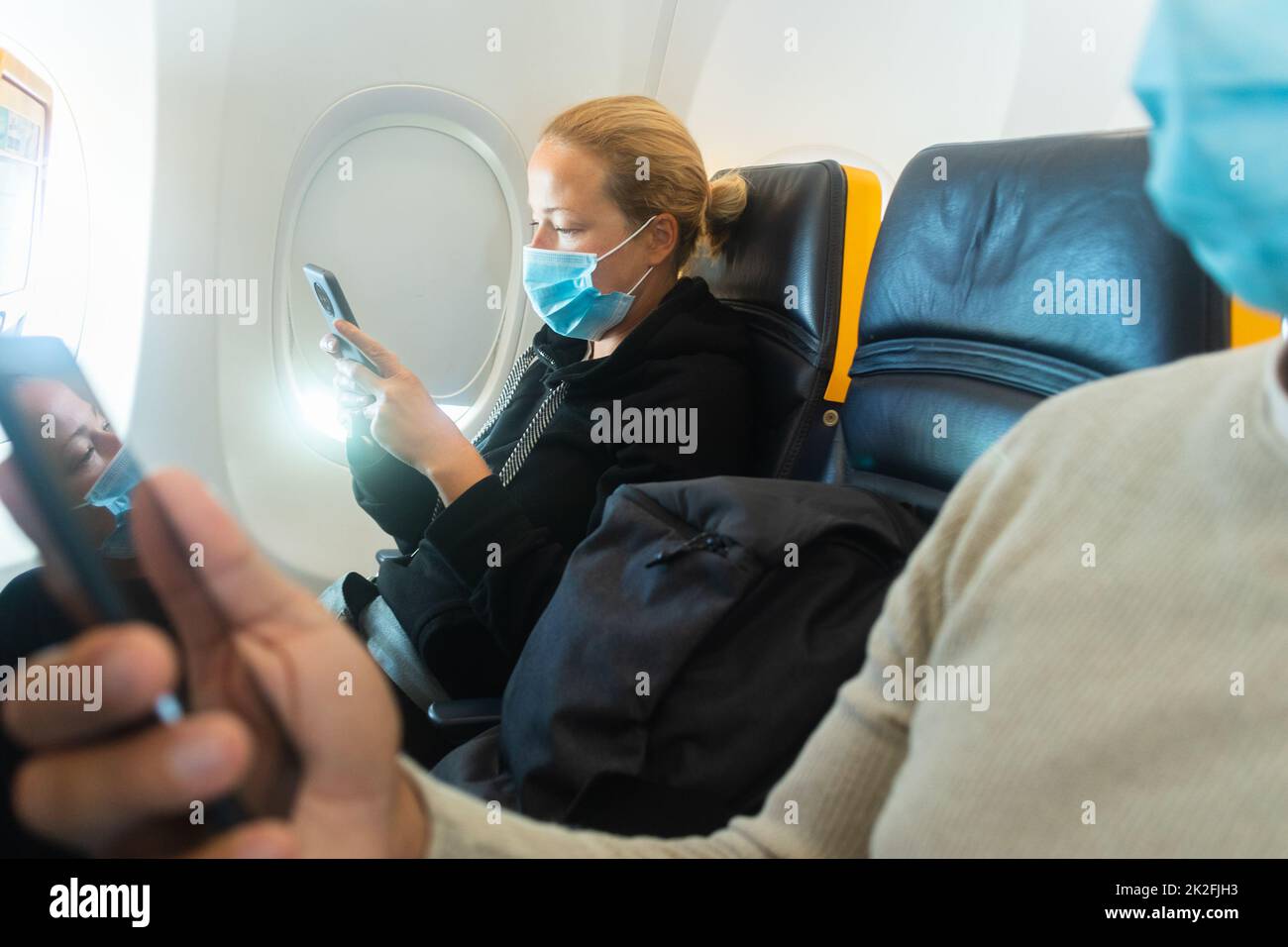A young couple wearing face mask, using smart phone while traveling on ...