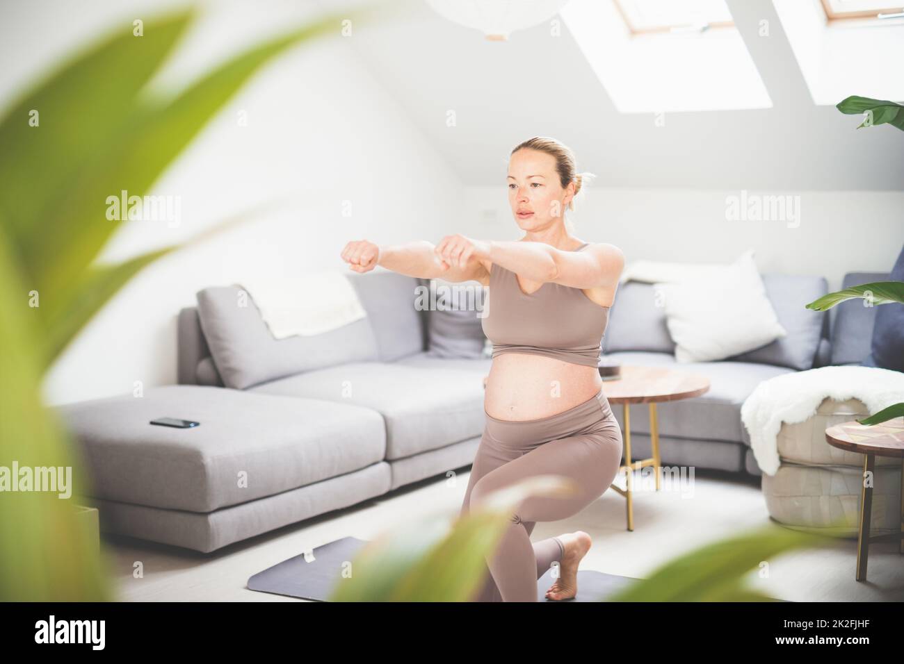 Young beautiful pregnant woman training pilates at home in her living ...