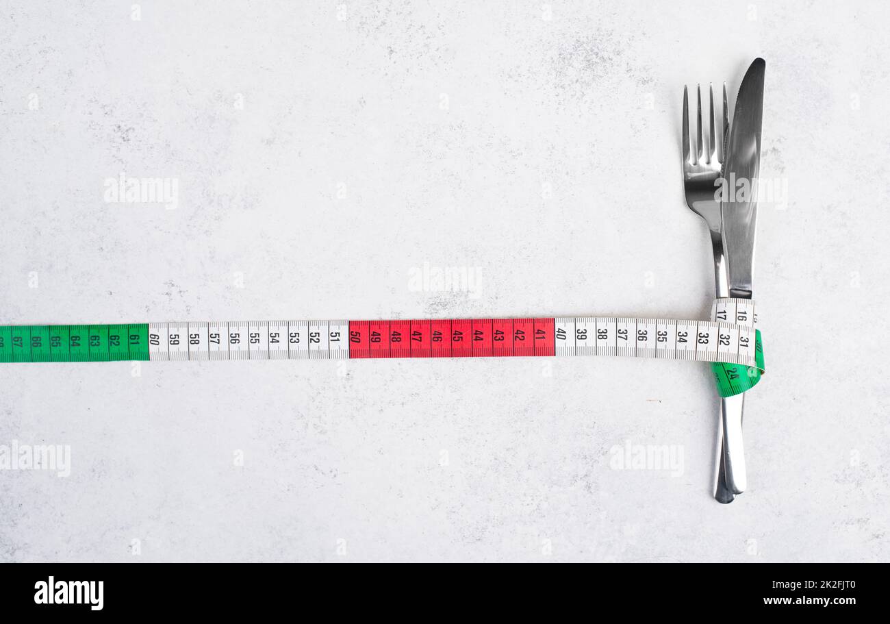 Fork and knife tight together with a tape measure, copy space for text ...
