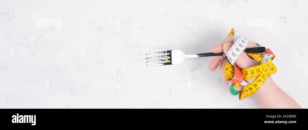 One single pea on a plate, hand with tape measure and fork, diet and ...