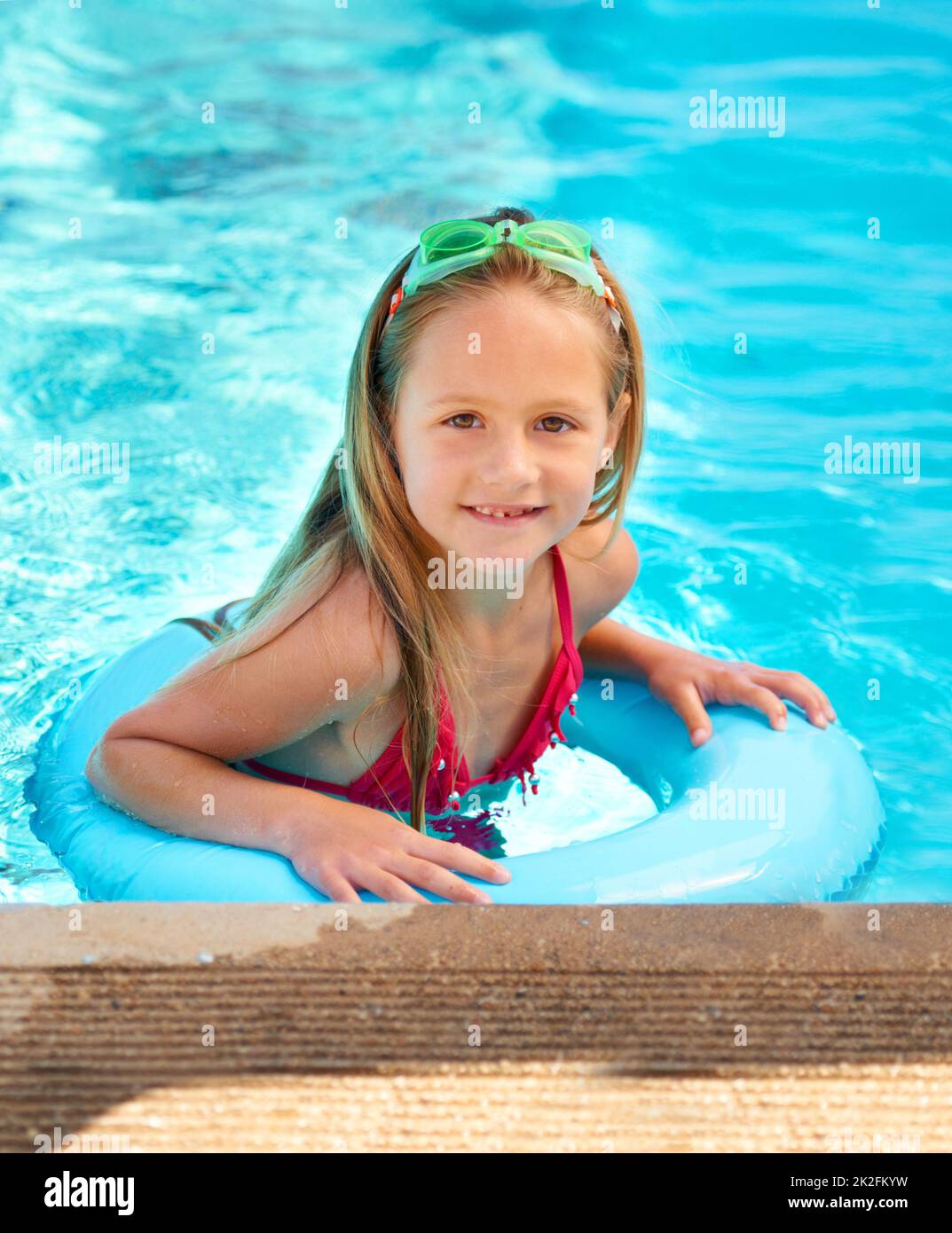 Shes a Summer child. A cute little girl using a pool inflatable while ...