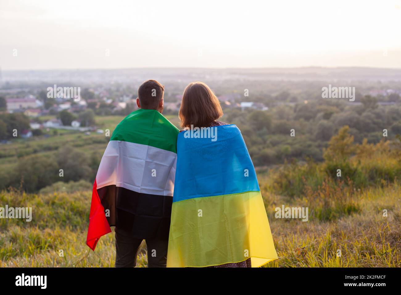 Couple covered in Ukraine and United Arab Emirates flags. Concept of ...