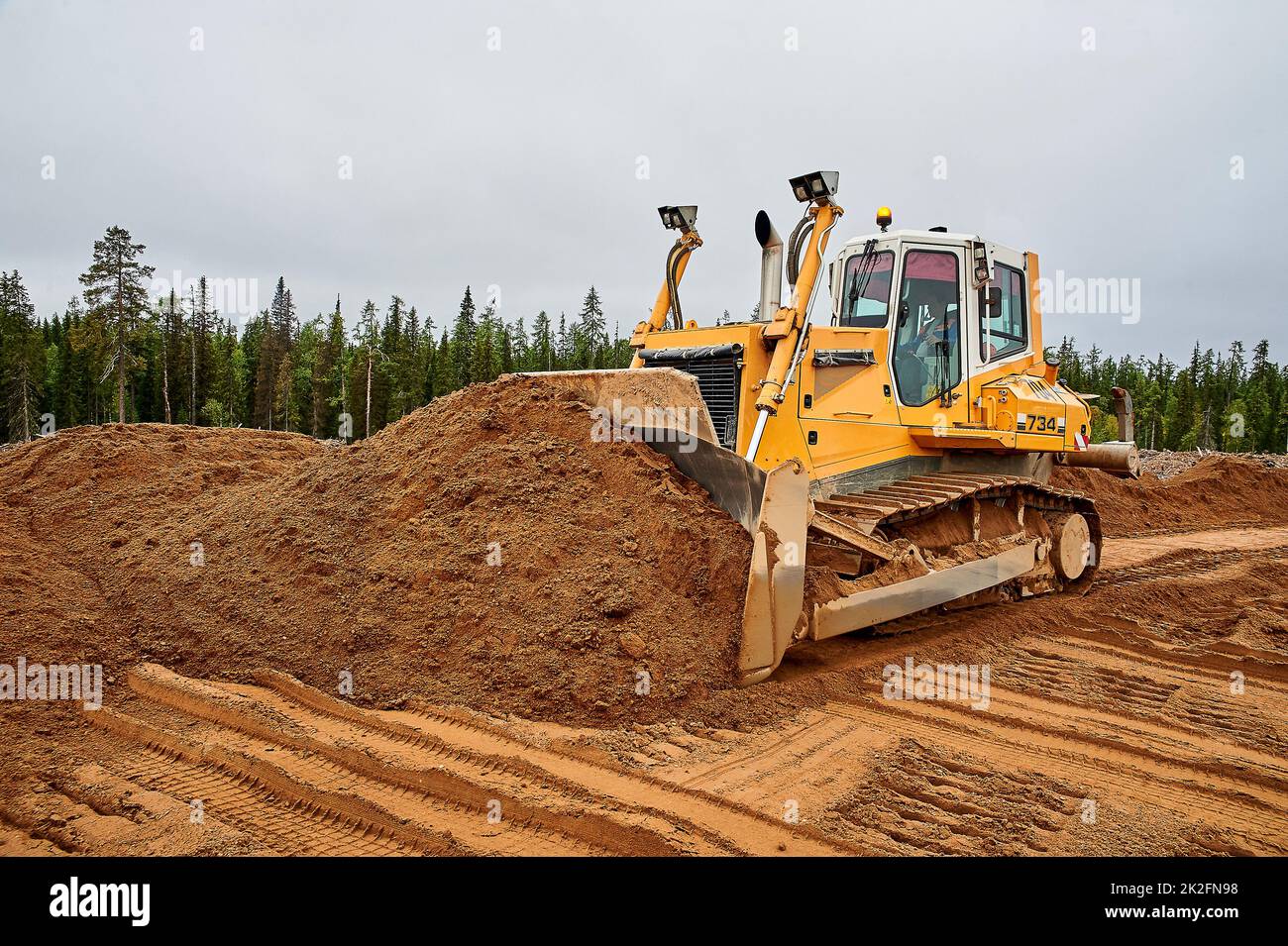 A yellow tractor levels the site with sand Stock Photo - Alamy