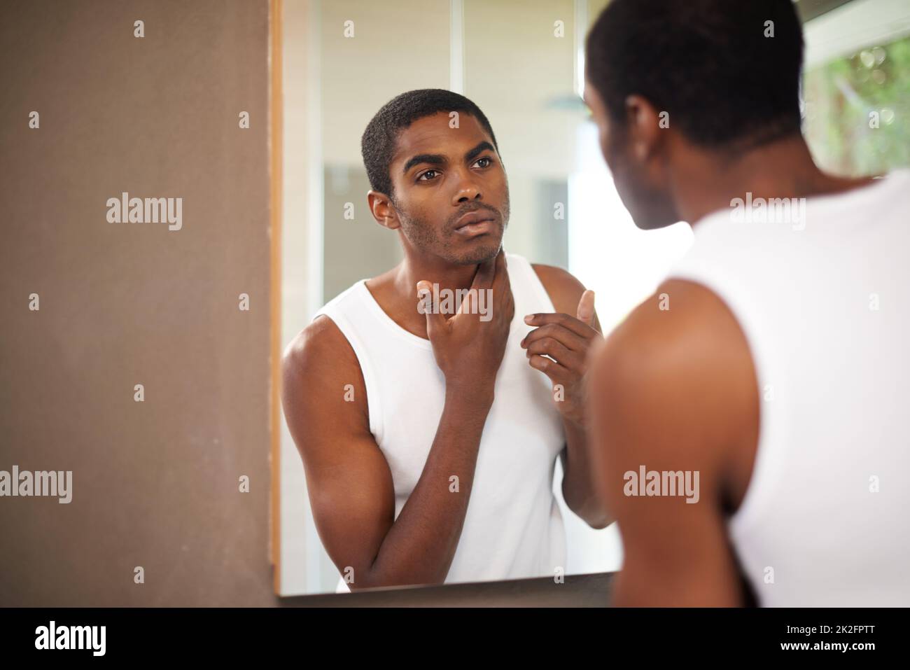 He takes care of his skin. A young man applying cream to his face while ...