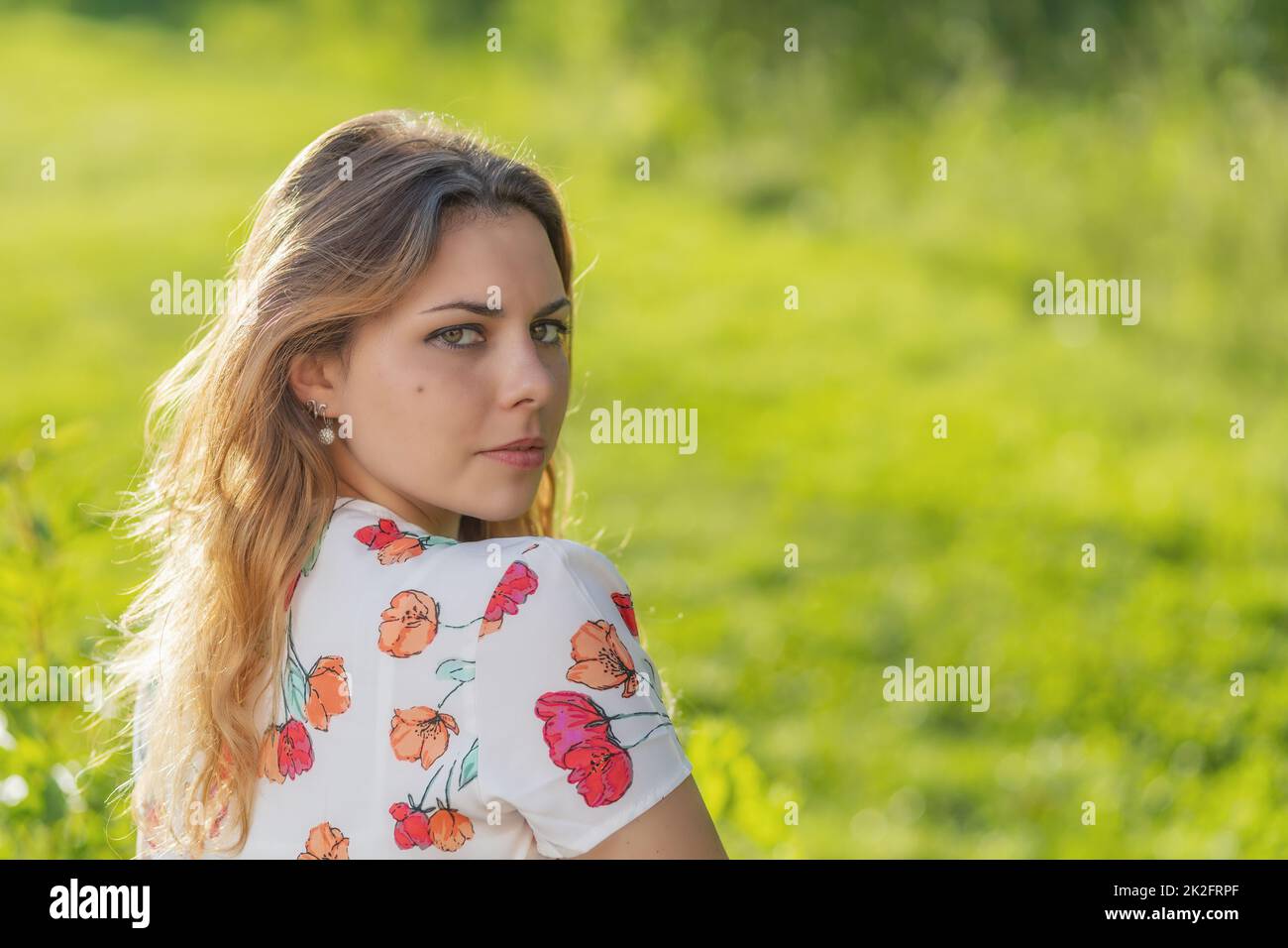 Young woman is looking over her shoulder at the camera outdoors Stock ...