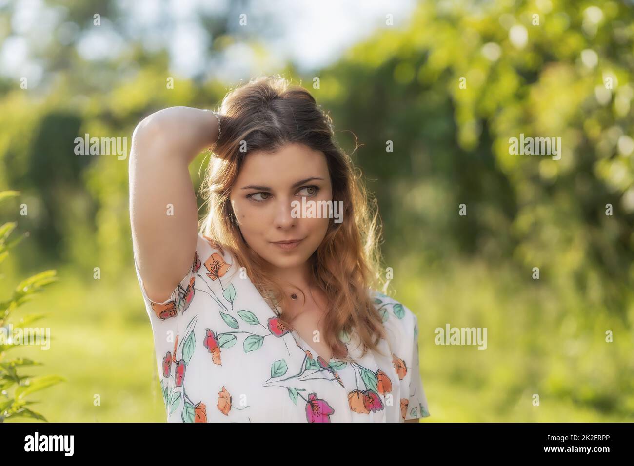 young woman is posing outdoors looking at the side Stock Photo - Alamy