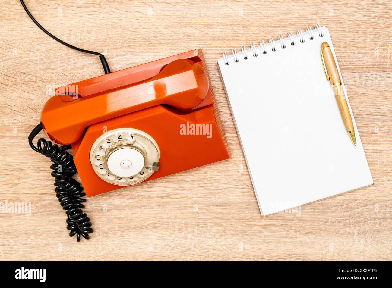 Orange rotary telephone and blank notebook with a pen Stock Photo - Alamy