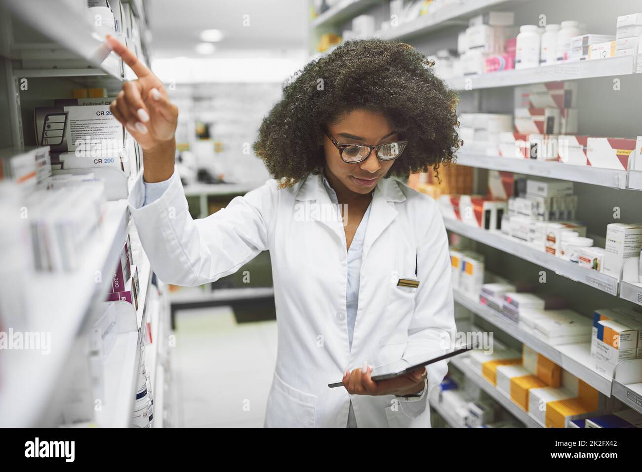 This is in the right place. Shot of a cheerful young female pharmacist ...