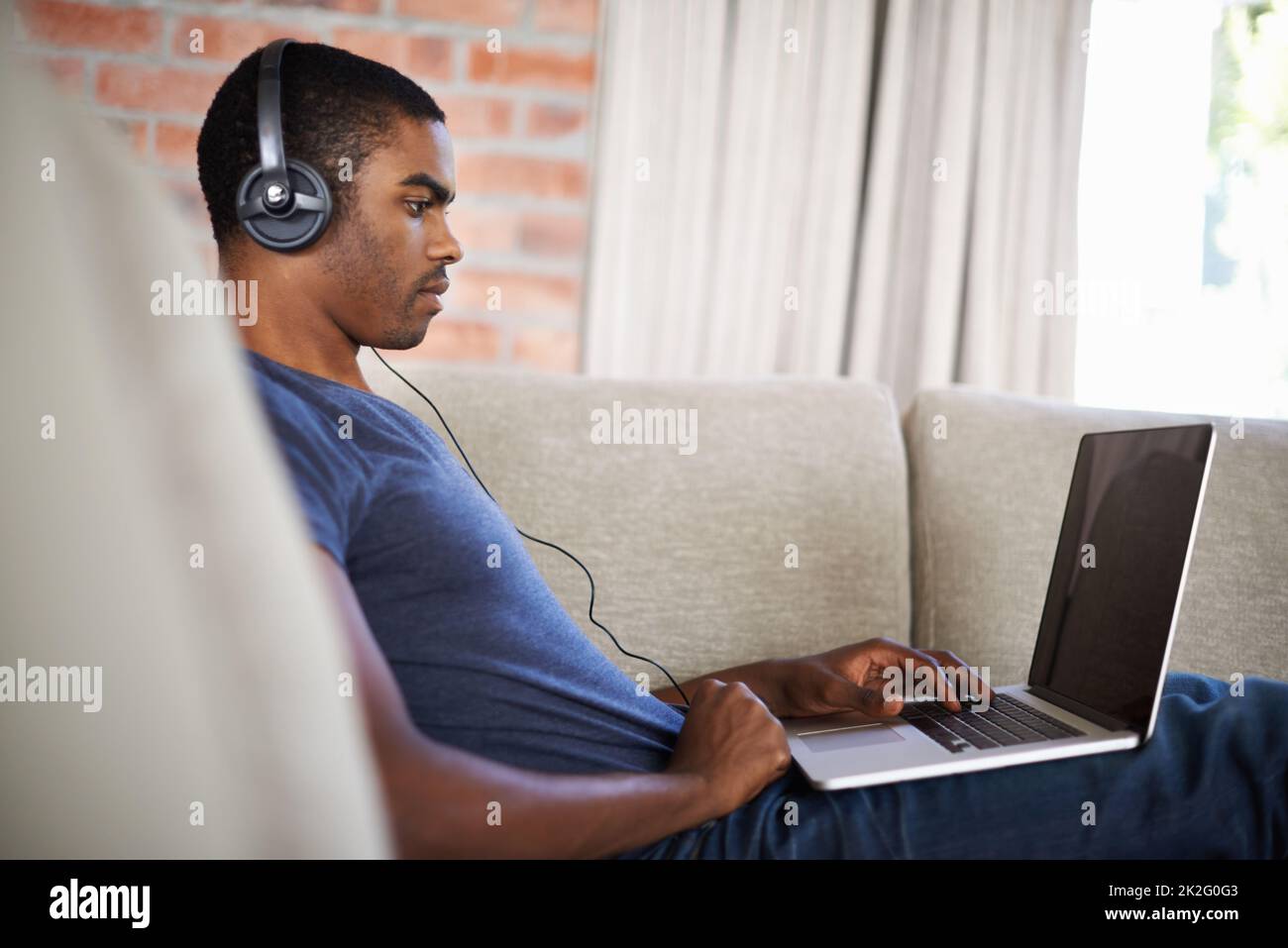 Focused on his work. a handsome young man using his laptop while ...