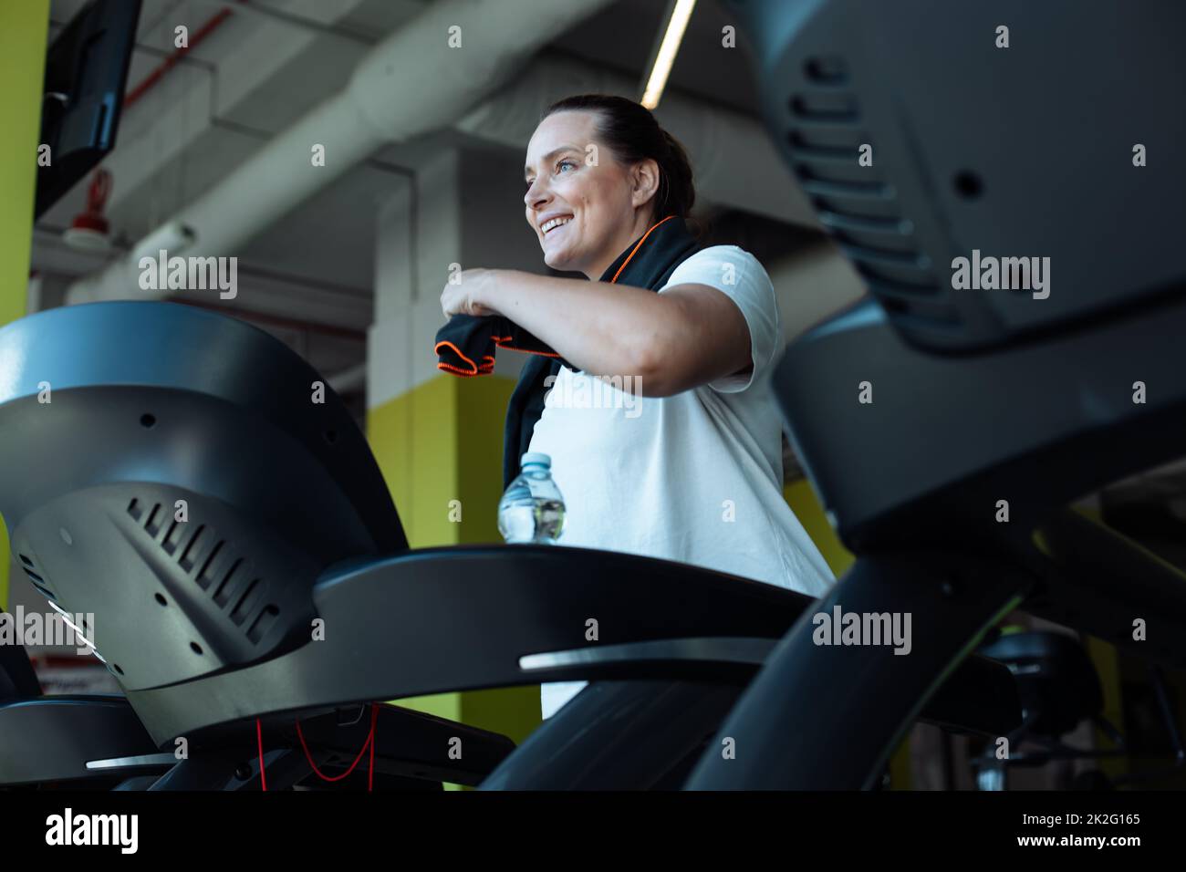 Happy plus size woman vigorously run on modern treadmill at fitness gym ...
