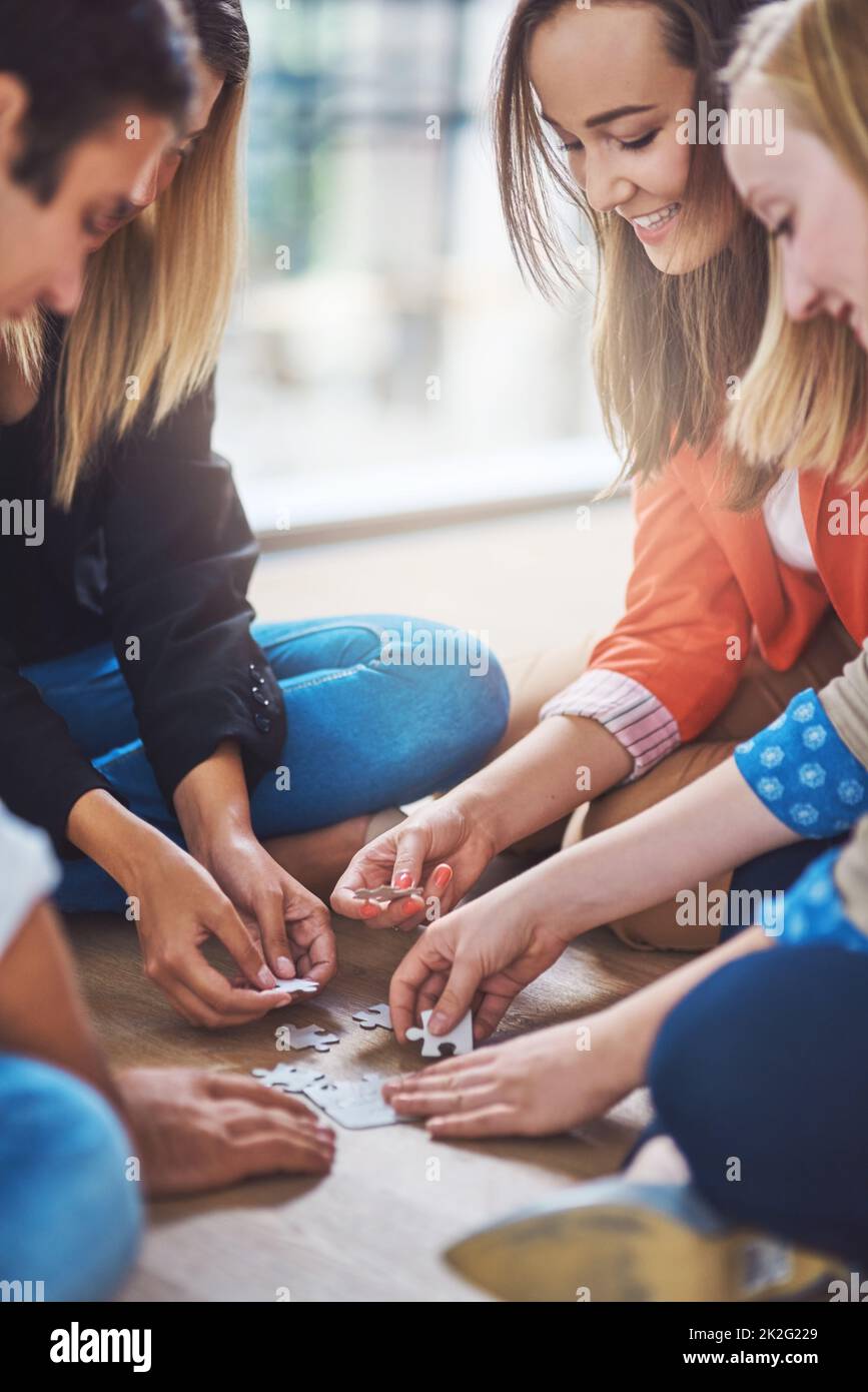 Collaborating as a team. Shot of a group of people building a puzzle ...