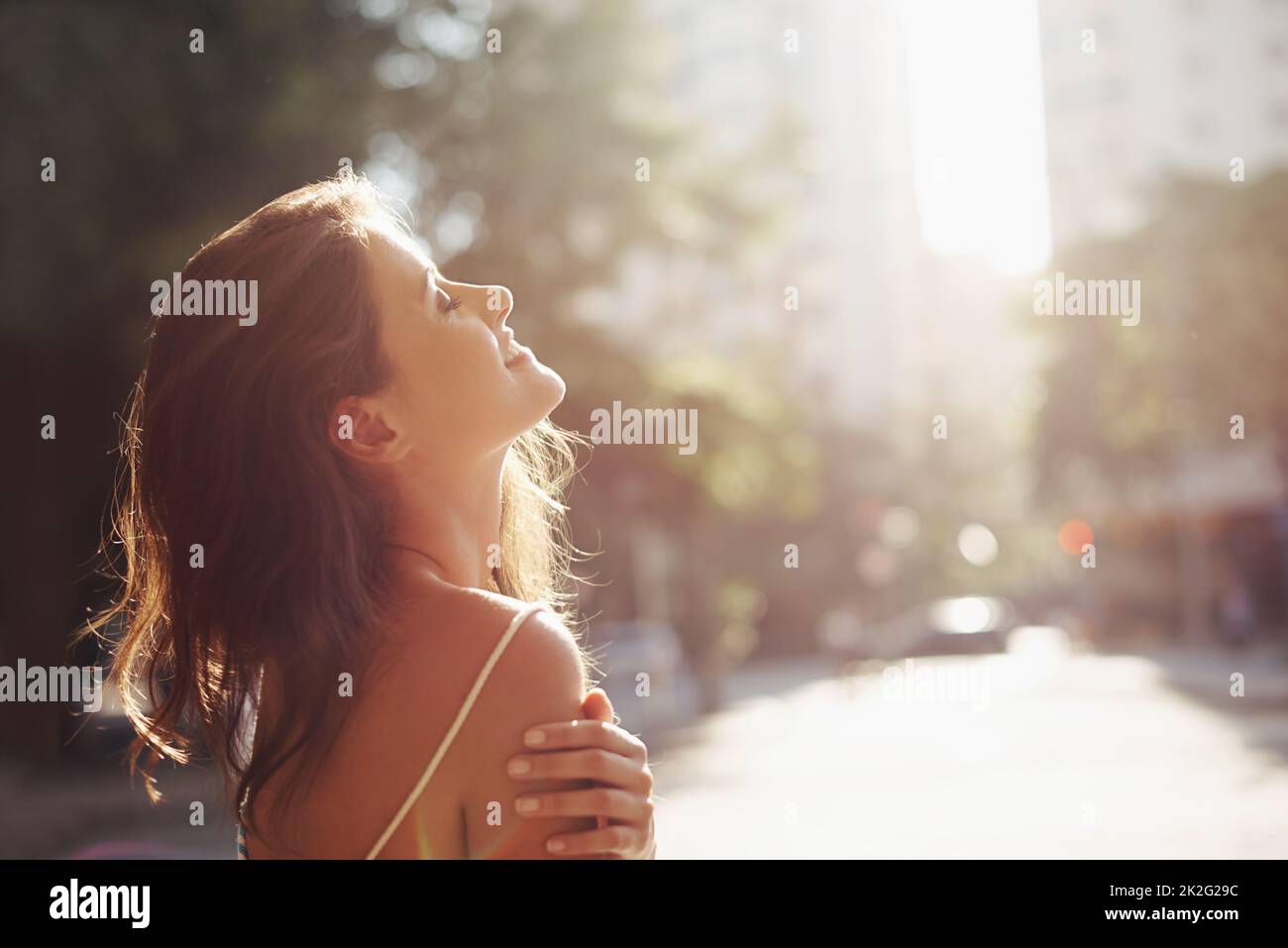Enjoying the sun on her skin. an attractive young woman in an urban ...