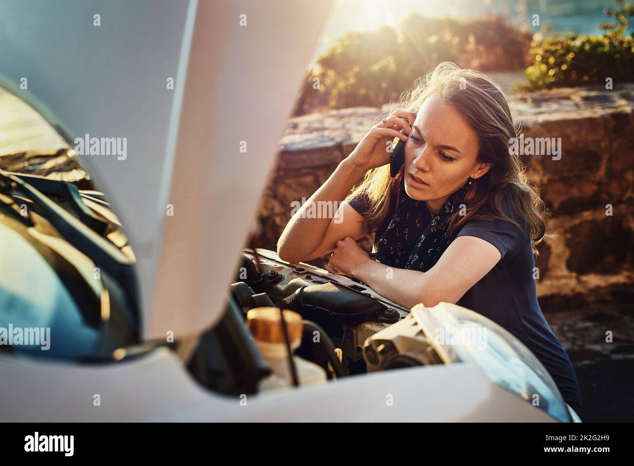 The engine just wont start. Cropped shot of a young woman calling roadside assistance after ...