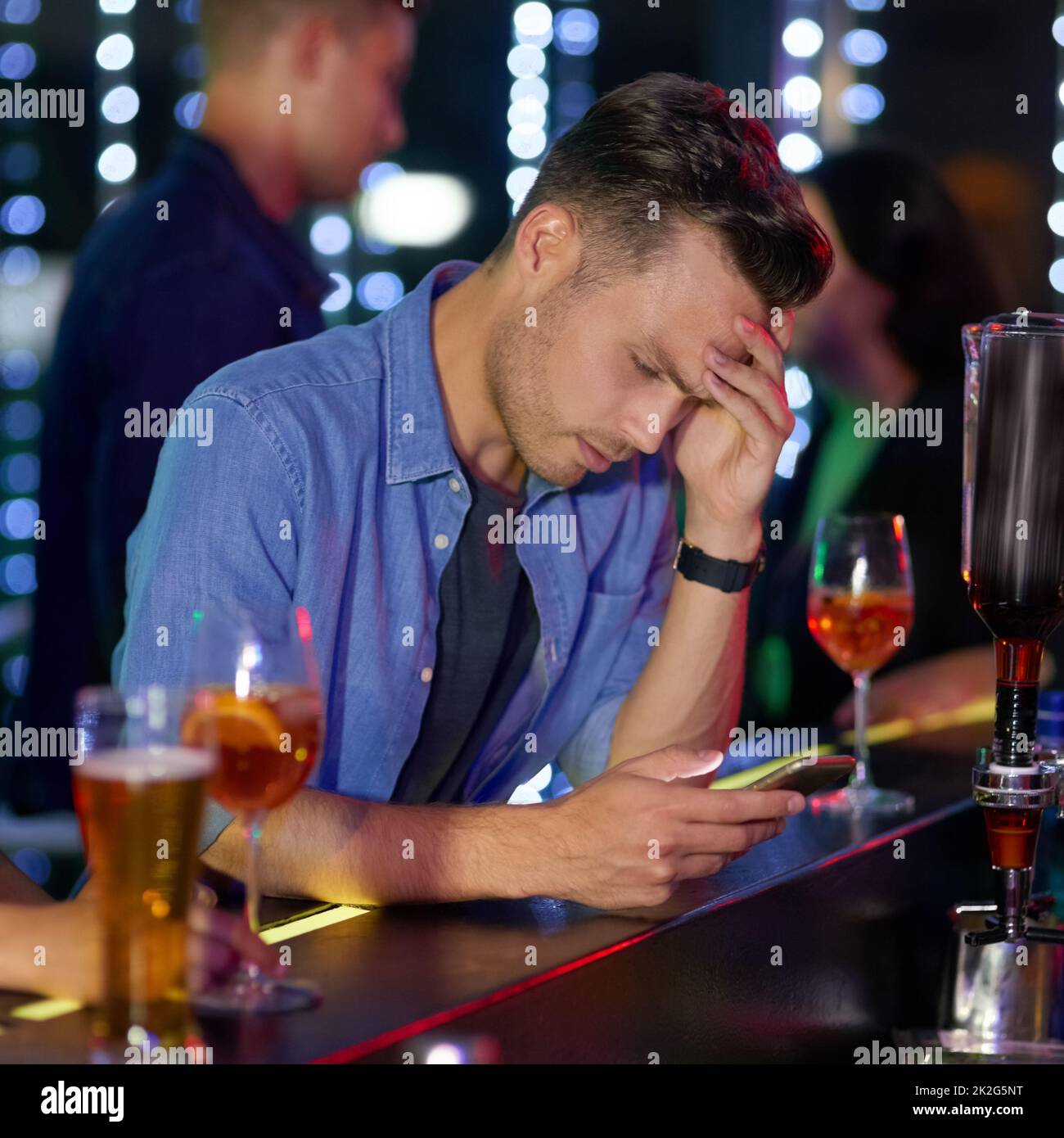 Stood up again. Shot of an upset looking young man reading a text on ...