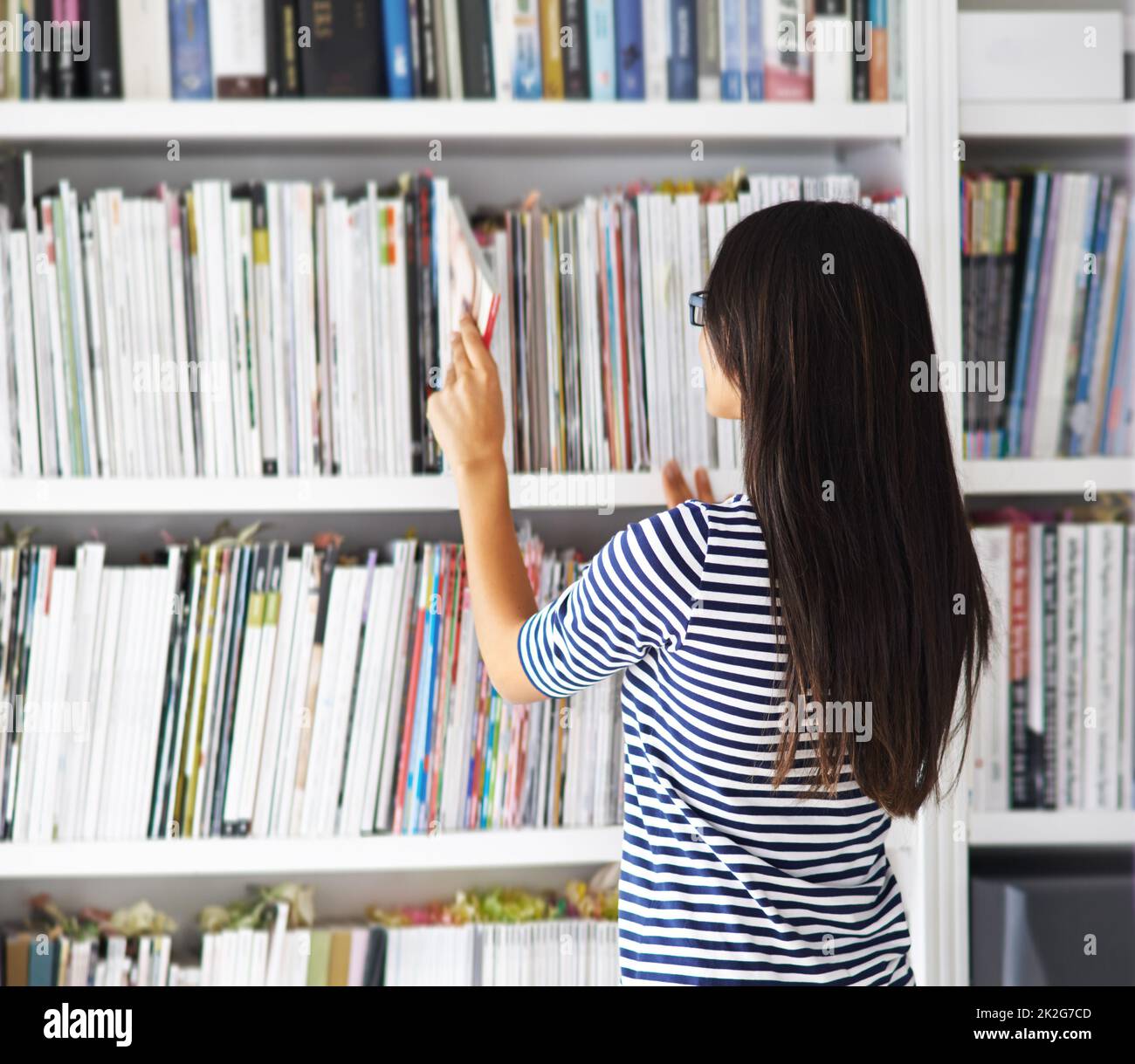 Woman looking through bookshelf hi-res stock photography and images - Alamy