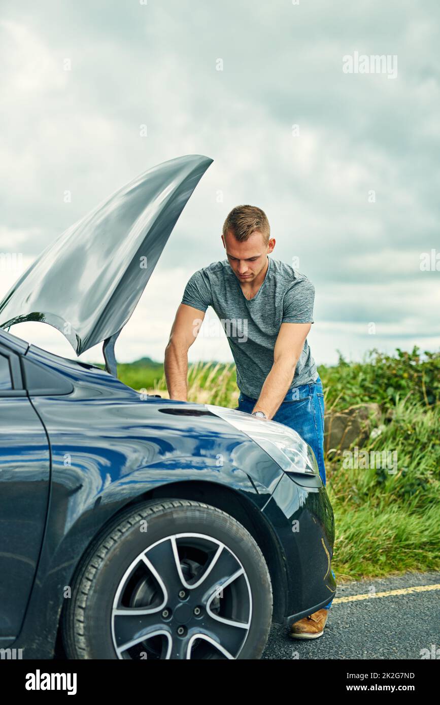Lets see whats wrong with this thing. Shot of a young man checking under the hood of his car ...