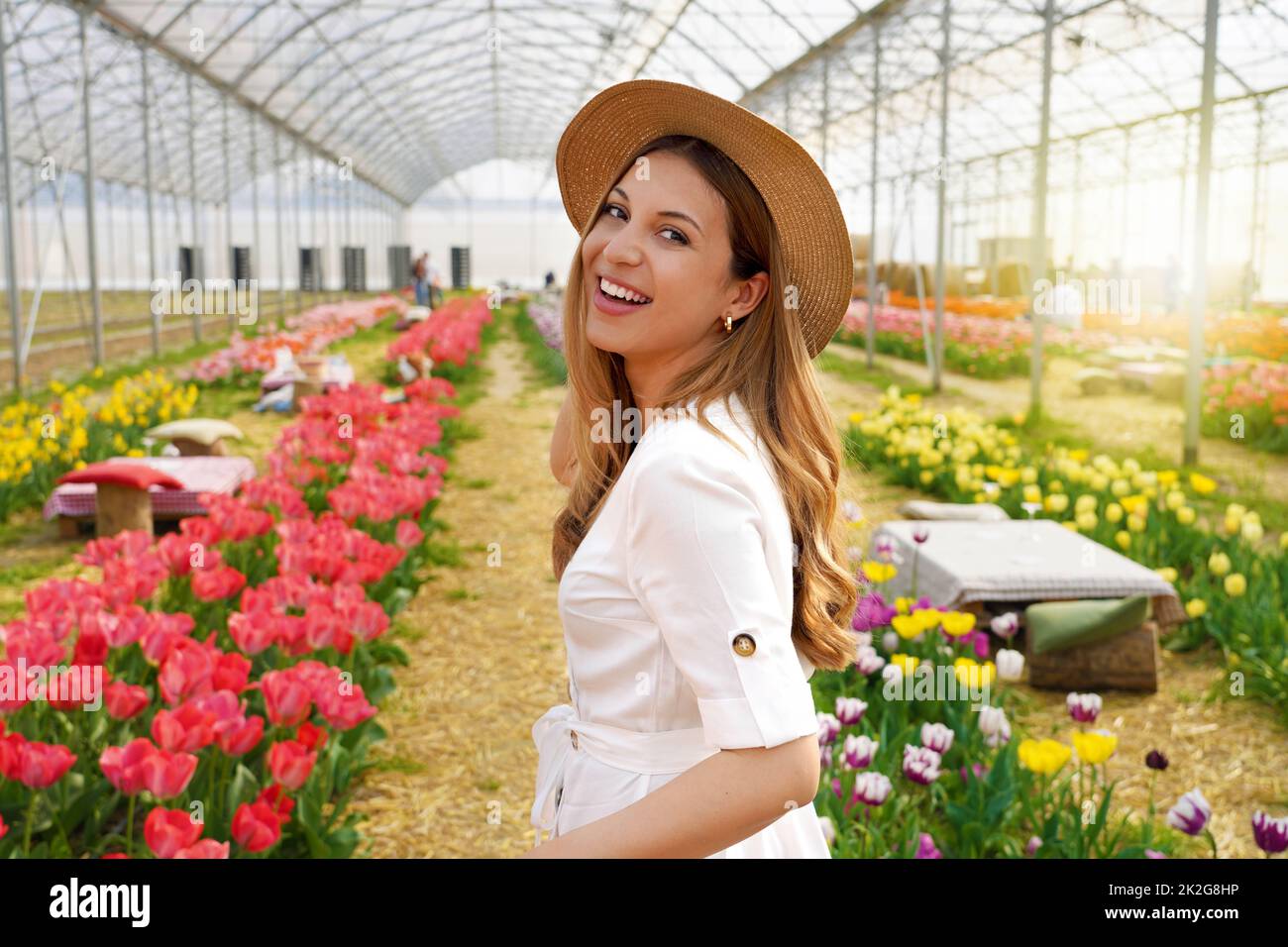 Laughing woman turns and looks to the camera walking between tulips and ...