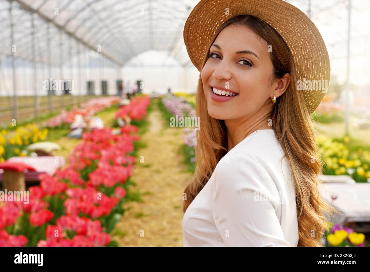 Close-up of fresh girl with straw hat turn to camera in the garden on ...