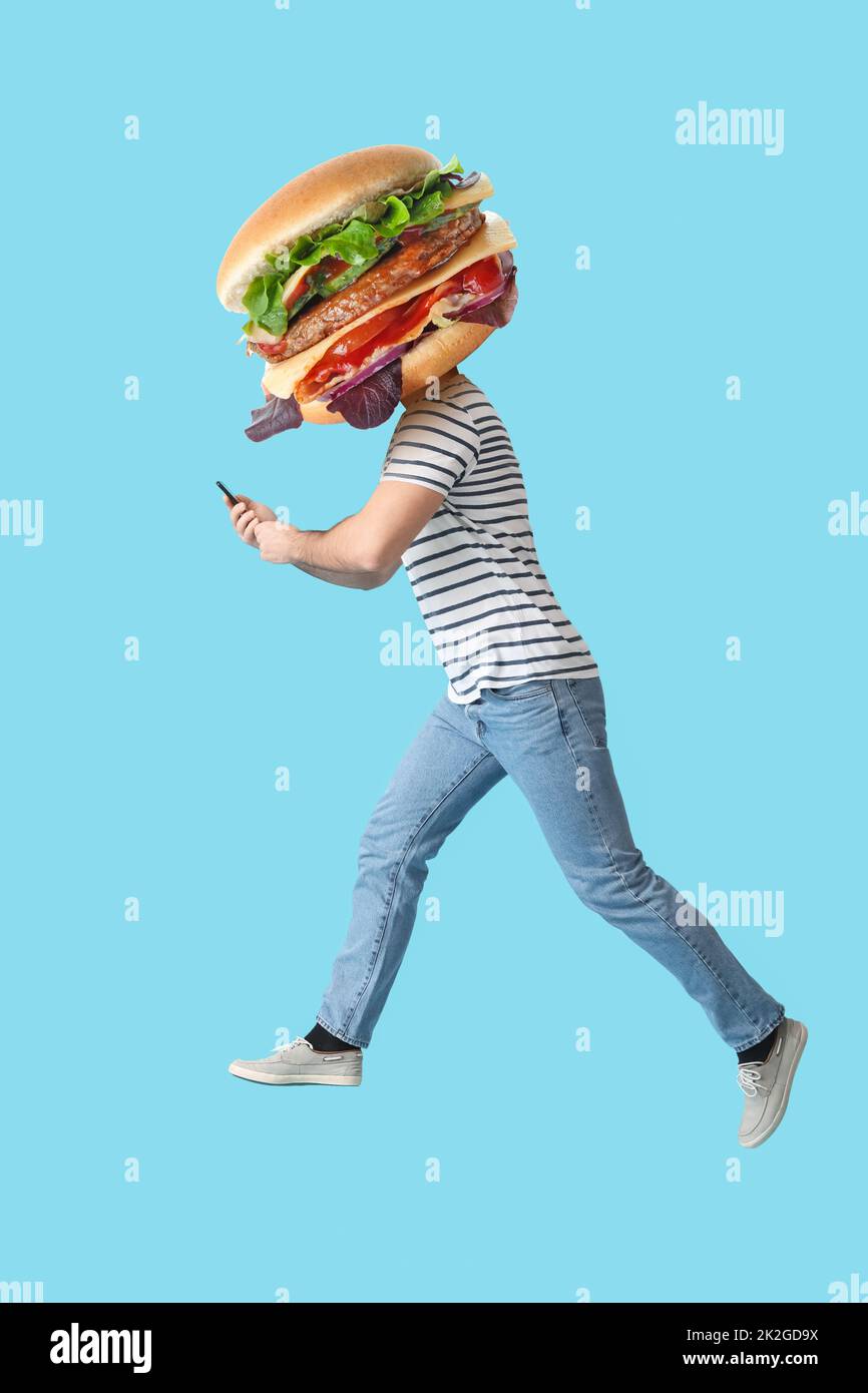 Jumping man with tasty burger instead of his head and smartphone on ...