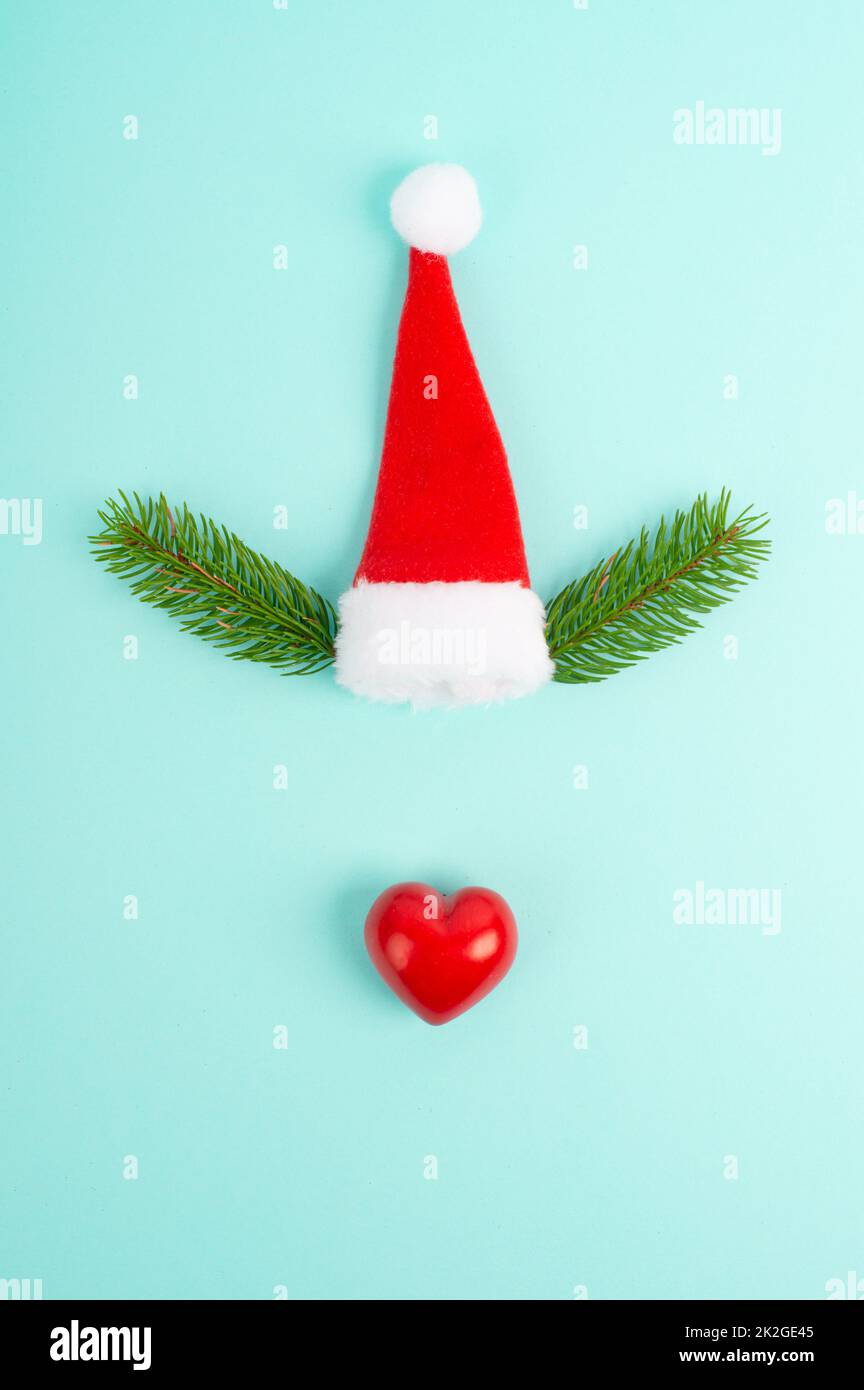 Face of a reindeer with a red heart nose, fir antlers and a santa claus ...