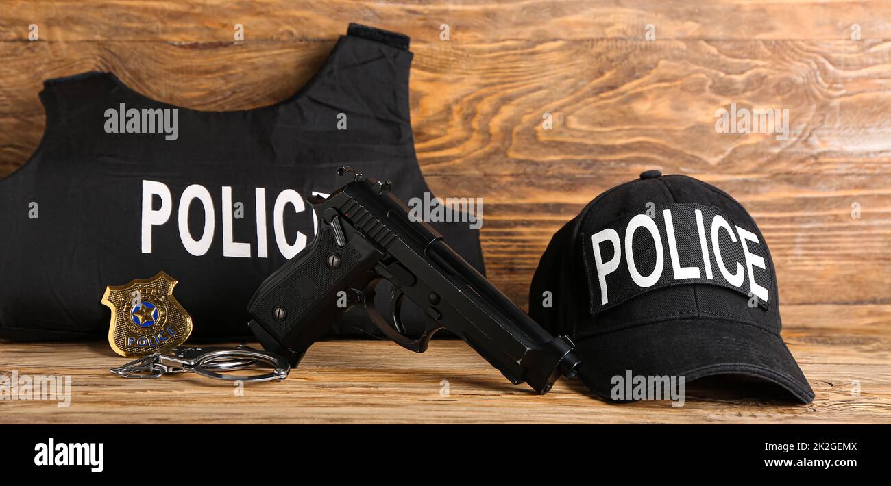 Uniform of policeman with gun and handcuffs on wooden background Stock ...