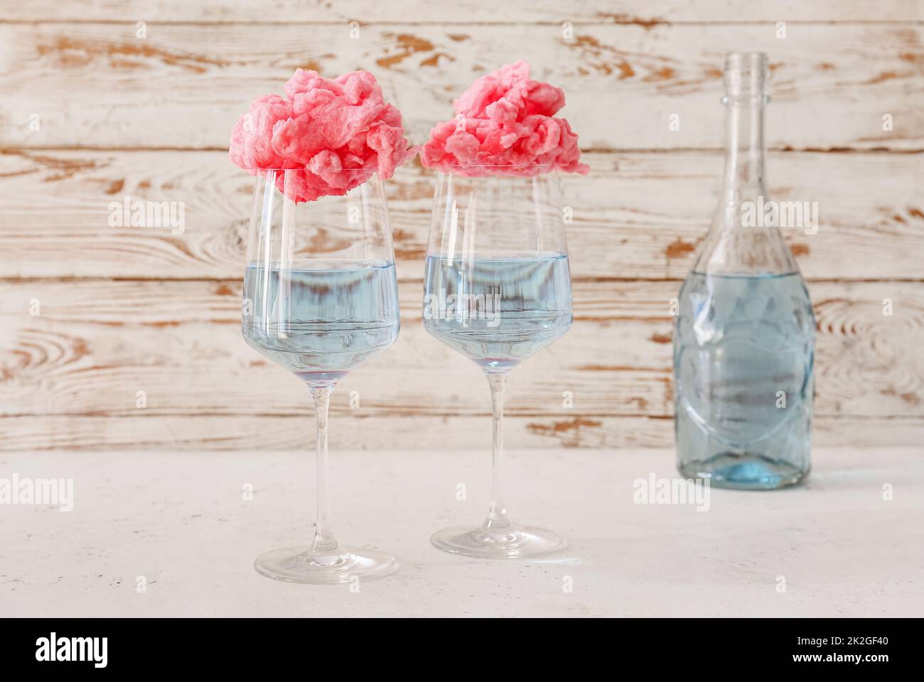 Bottle and glasses with tasty cotton candy cocktail on light table ...