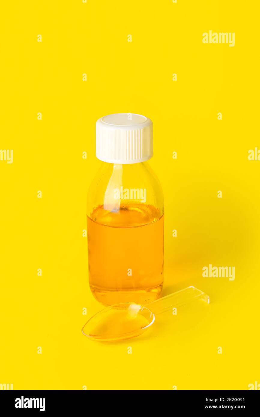 Bottle and spoon of cough syrup on yellow background Stock Photo - Alamy