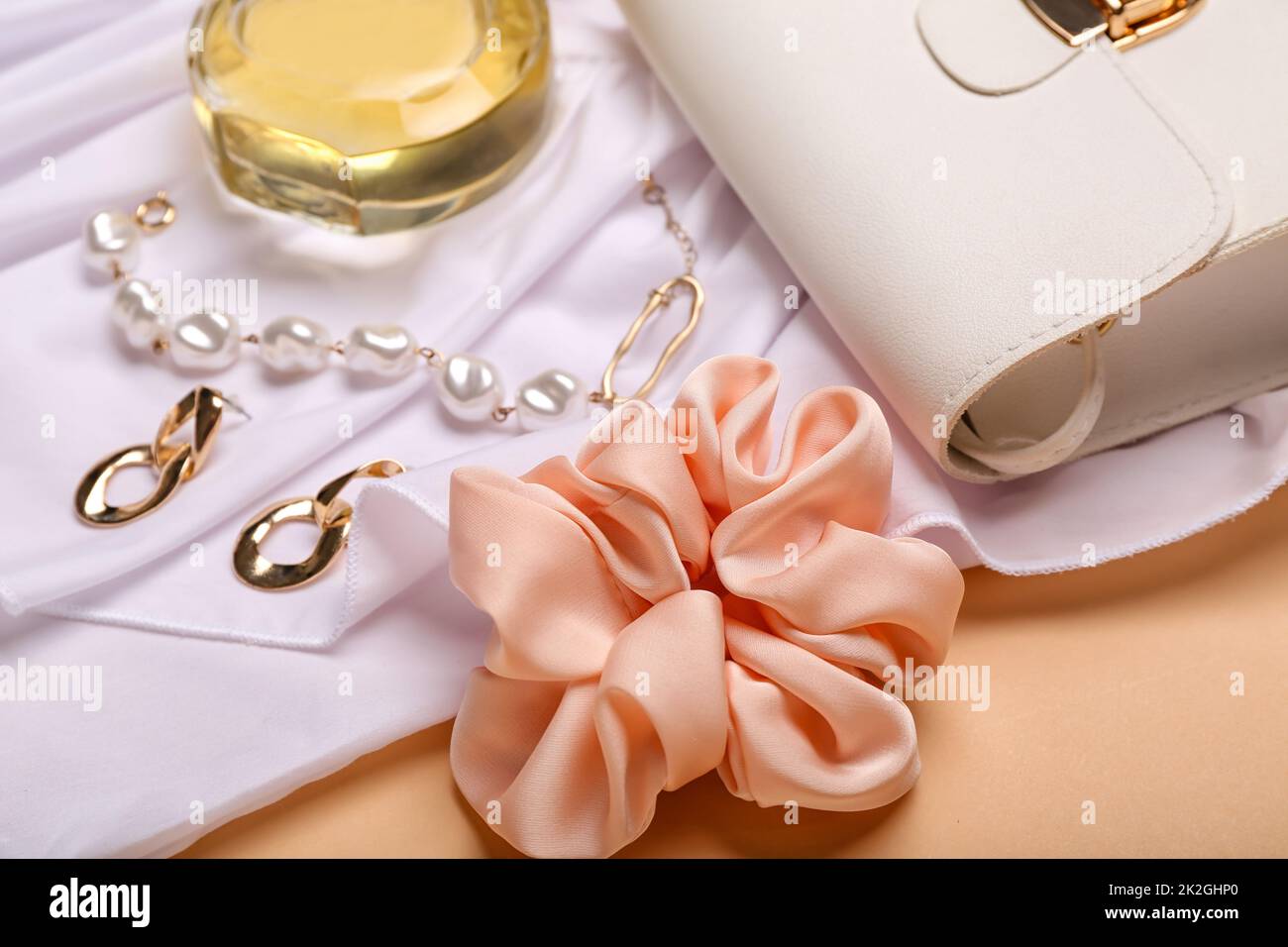 Stylish female accessories, clothes and perfume bottle on beige ...