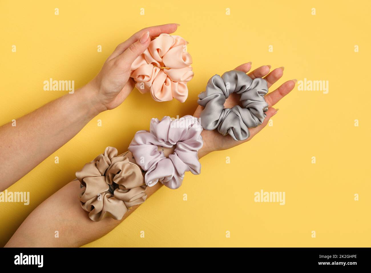 Female hands with different silk scrunchies on yellow background Stock ...
