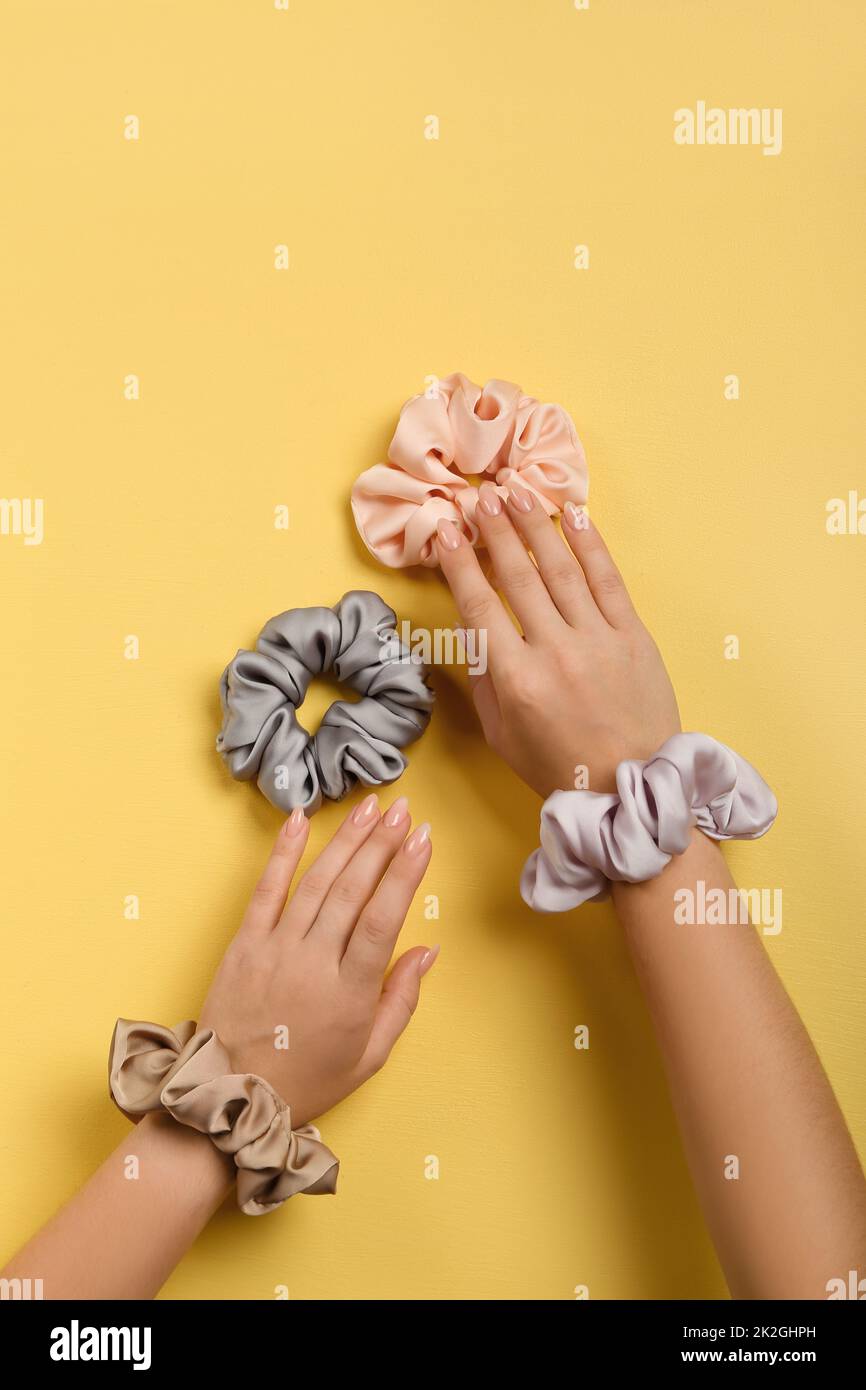 Female hands with silk scrunchies on yellow background Stock Photo - Alamy