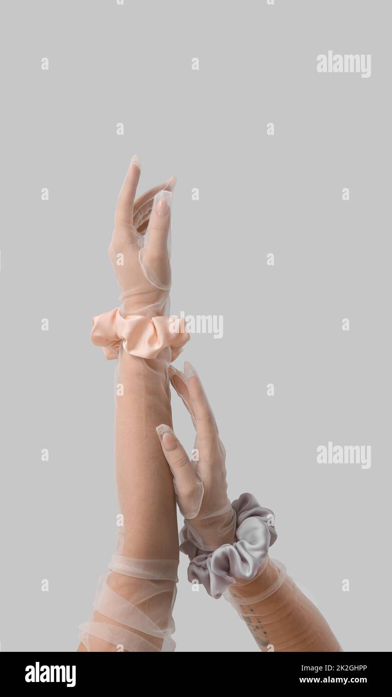 Female hands in gloves with silk scrunchies on light background Stock ...